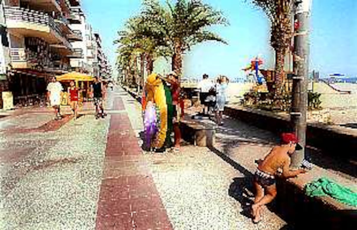 Paseantes y bañistas, en el paseo marítimo de la playa de Calafell ...